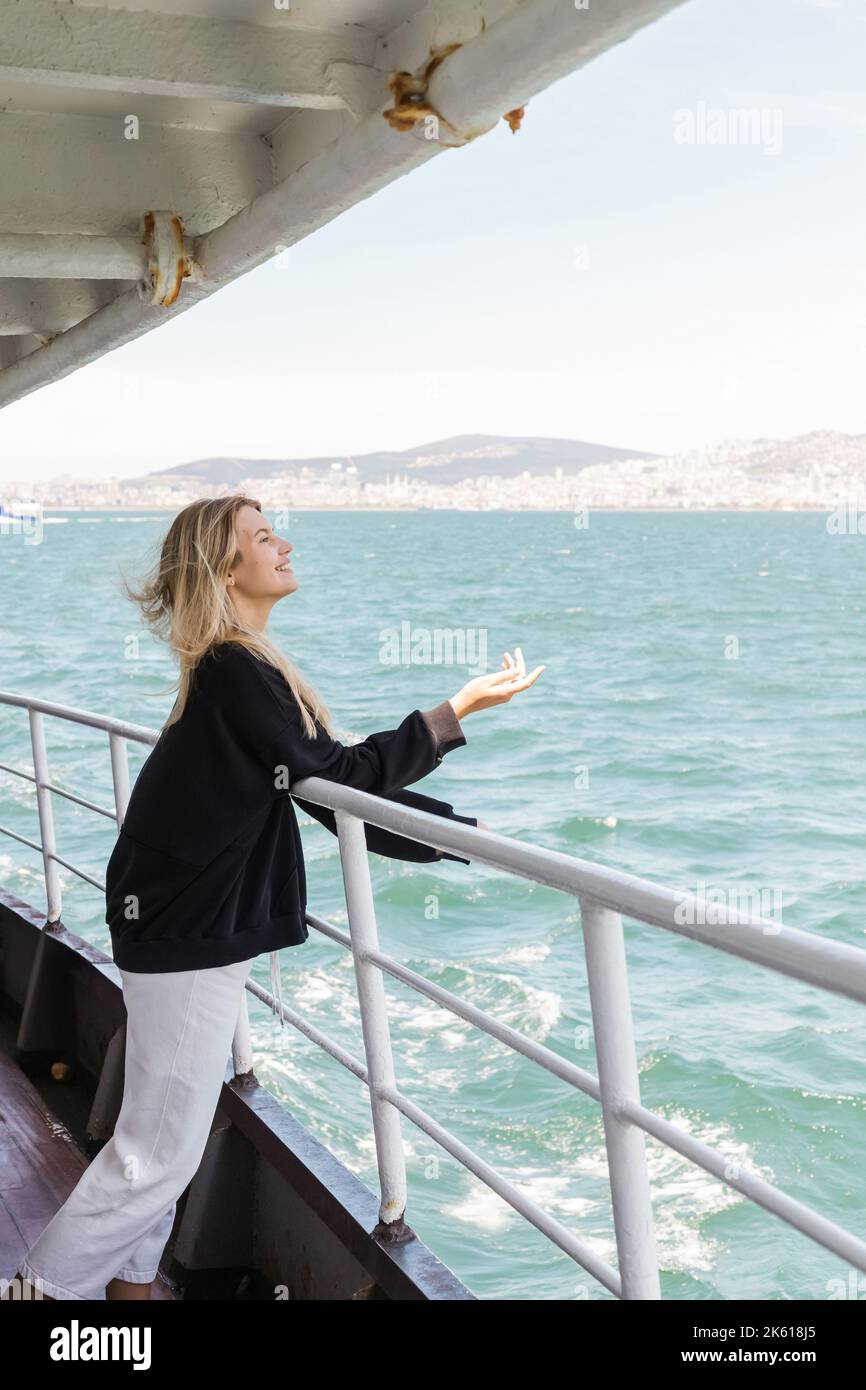 side view of woman in black sweater looking at sea from ferry boat ...