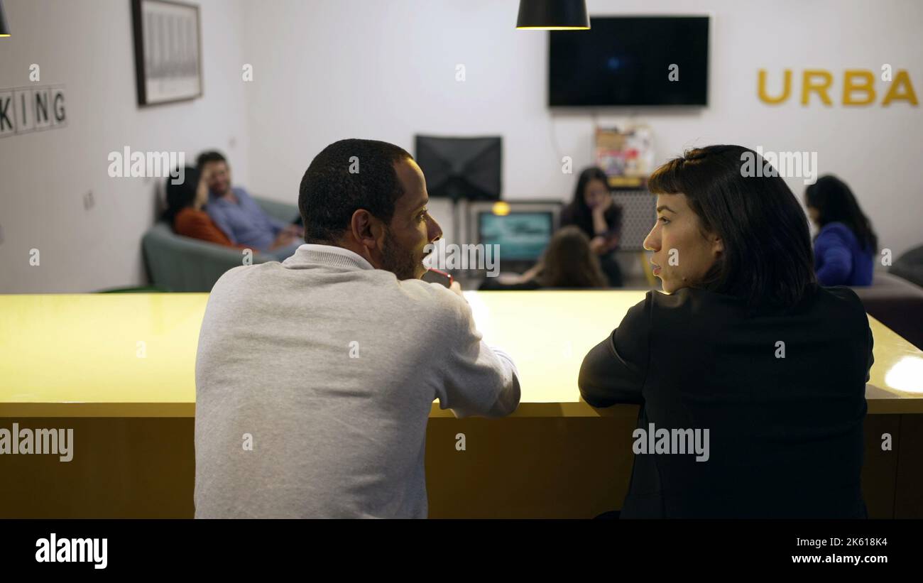 People conversing at workplace. Two diversed work colleagues talking at ...