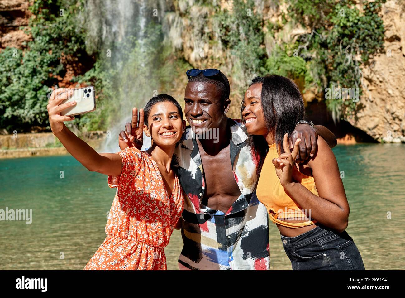 Cheerful diverse man and ladies taking self portrait on smartphone ...
