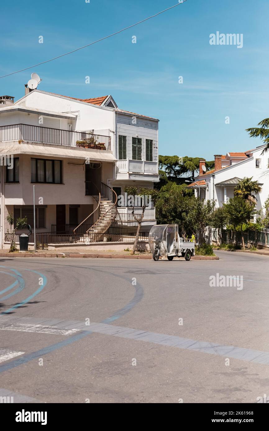 three wheeled moped with roof passing houses in princess islands in ...
