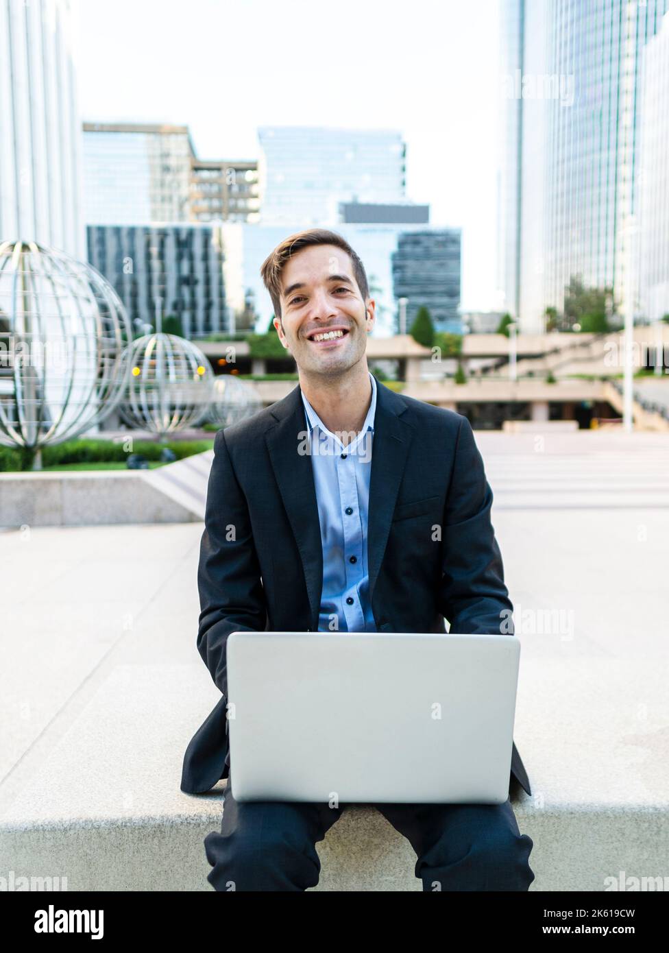 Positive guy in elegant suit sitting on bench in modern city and ...