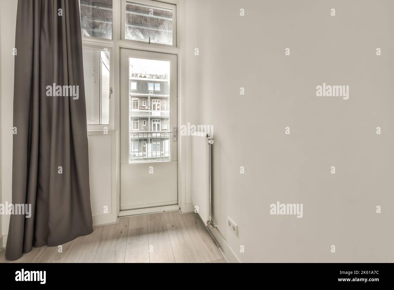 Room with door leading to balcony with metal fence overlooking street ...