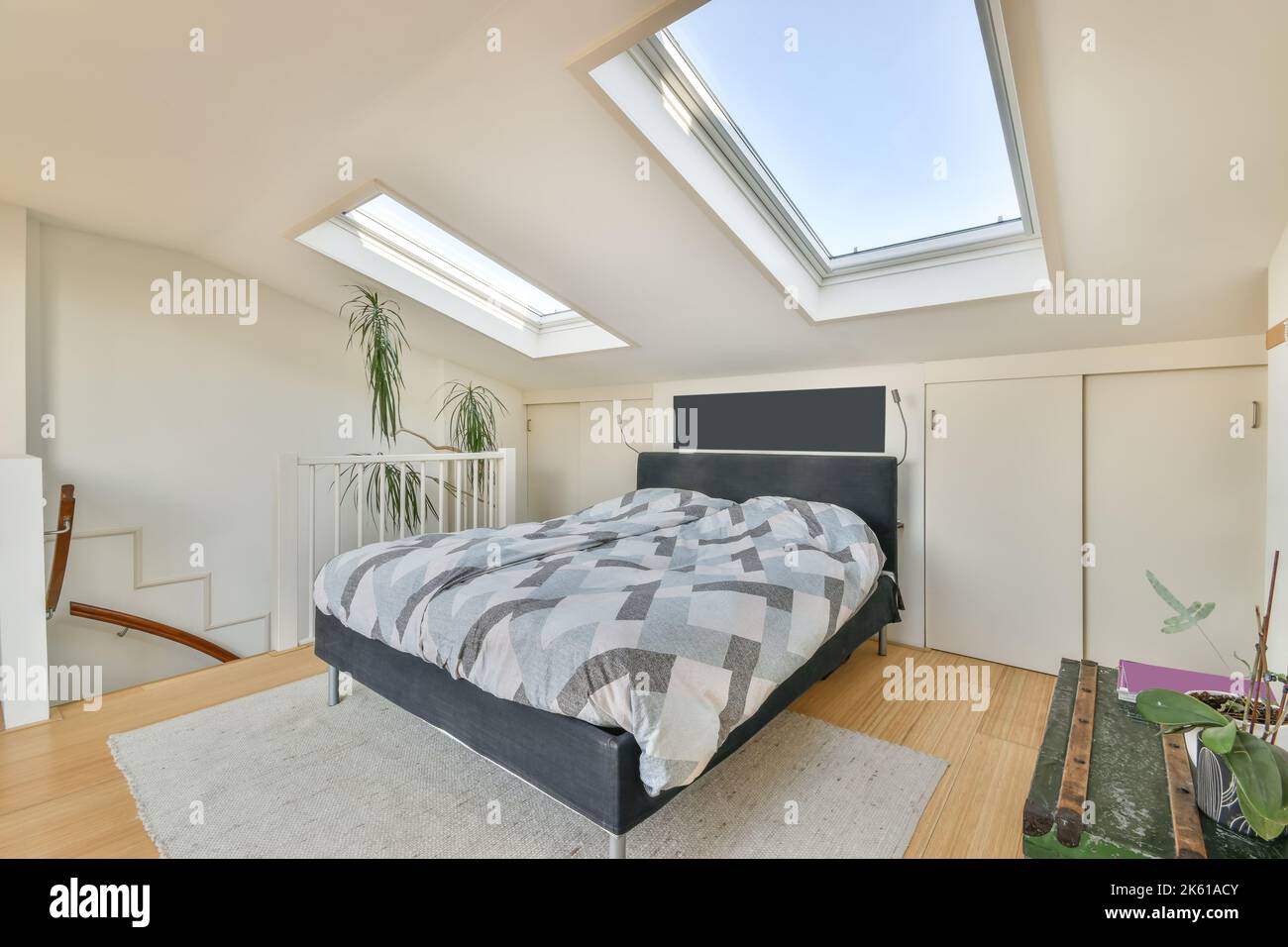 Comfortable bed located near window in light attic bedroom in modern ...