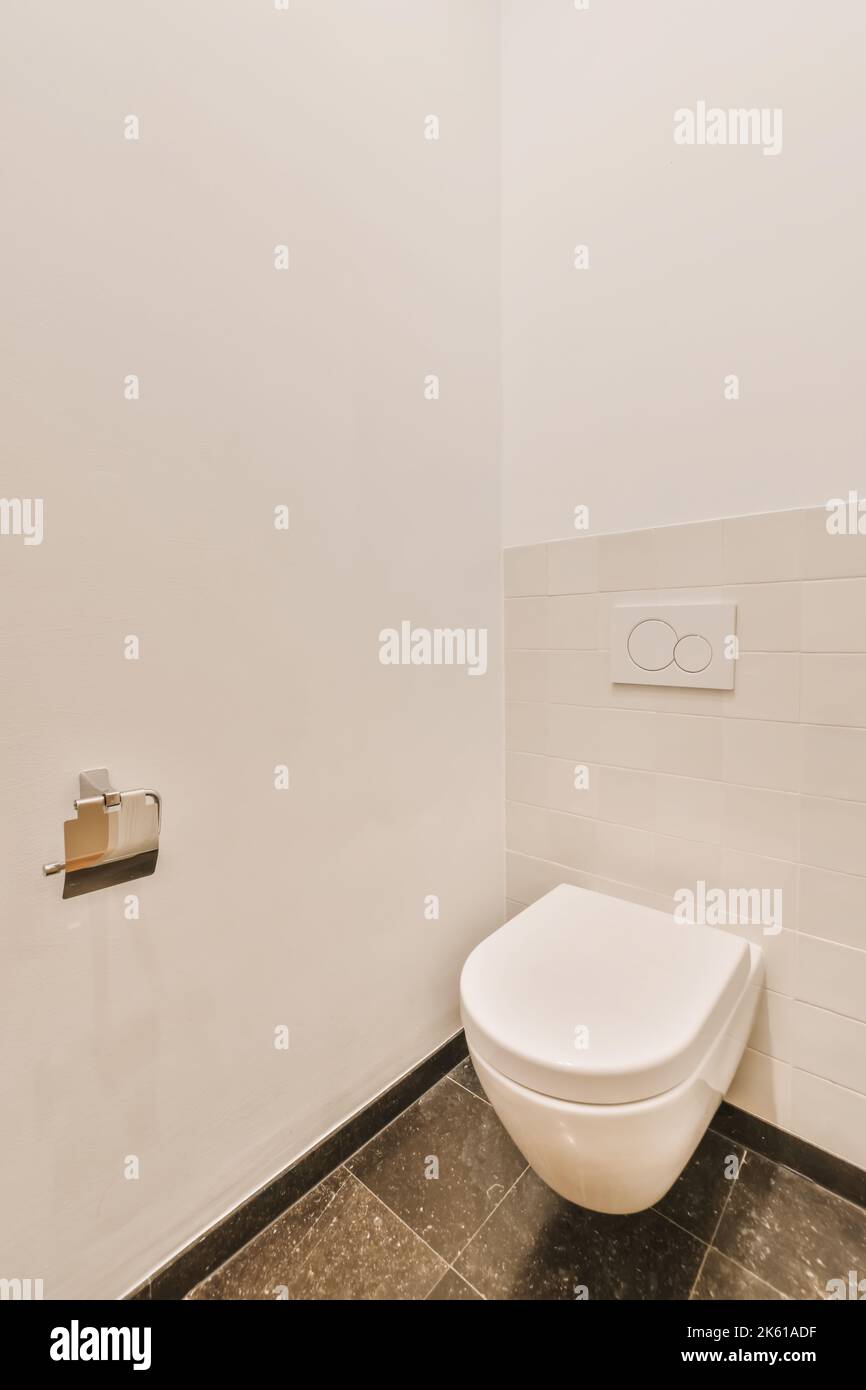 White ceramic toilet placed at white tiled wall in light stylish ...