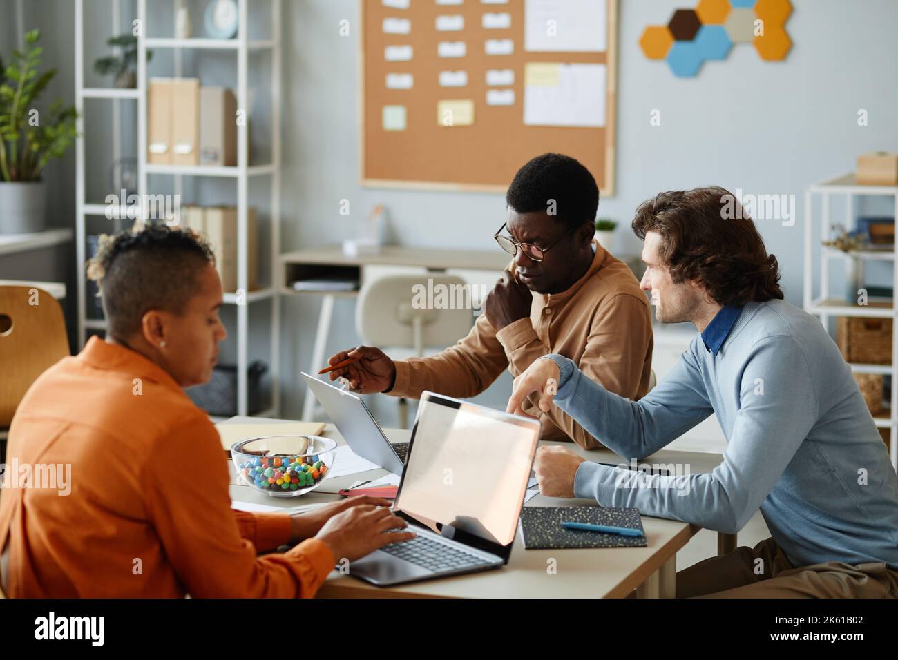 Portrait of busy business team using laptops while collaborating at ...