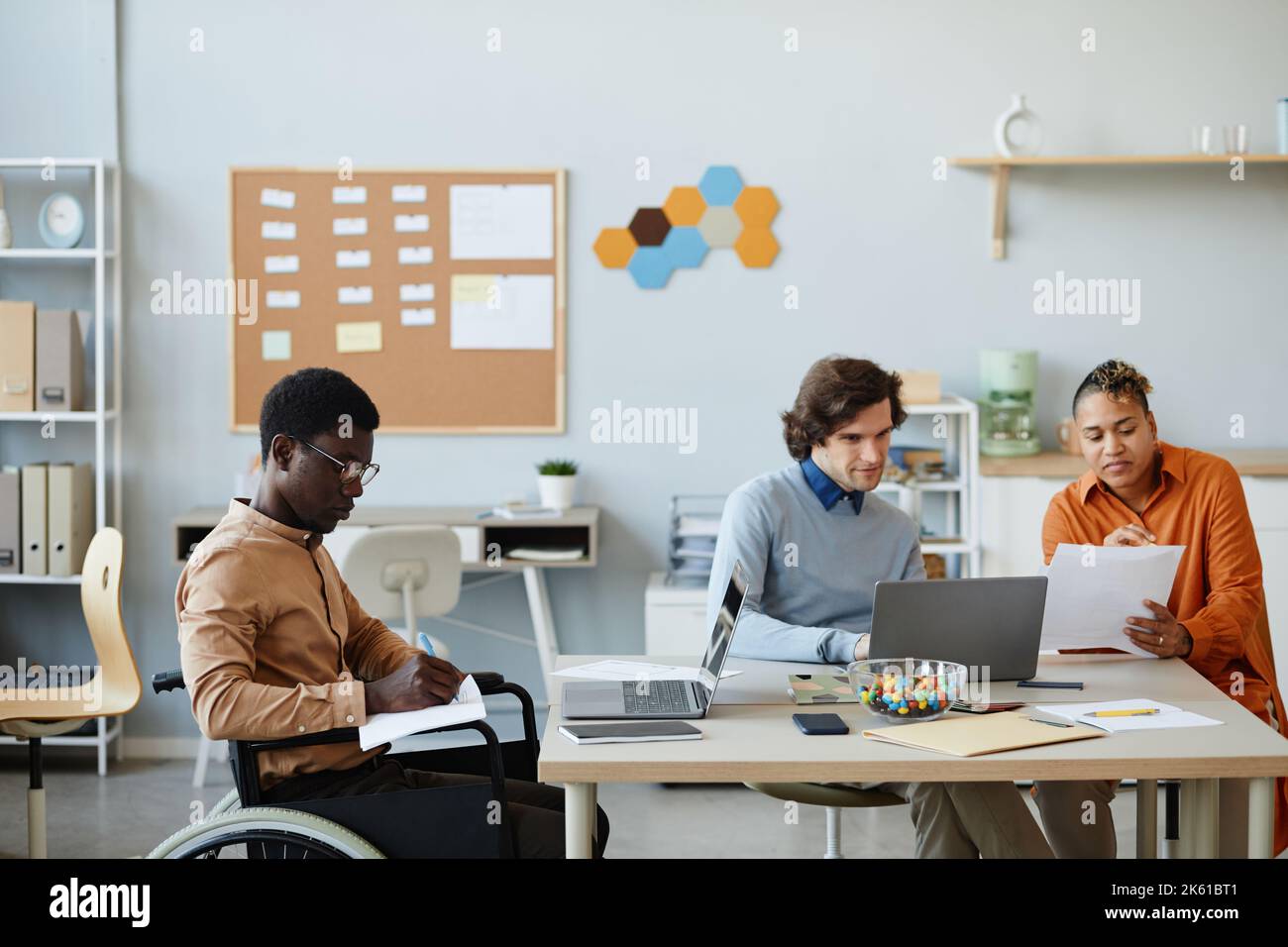Side view portrait of black young man with disability working in office ...