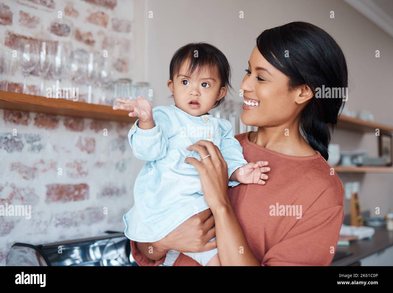 Love, happy mom and baby with down syndrome in kitchen in family home. Care, growth and support ...