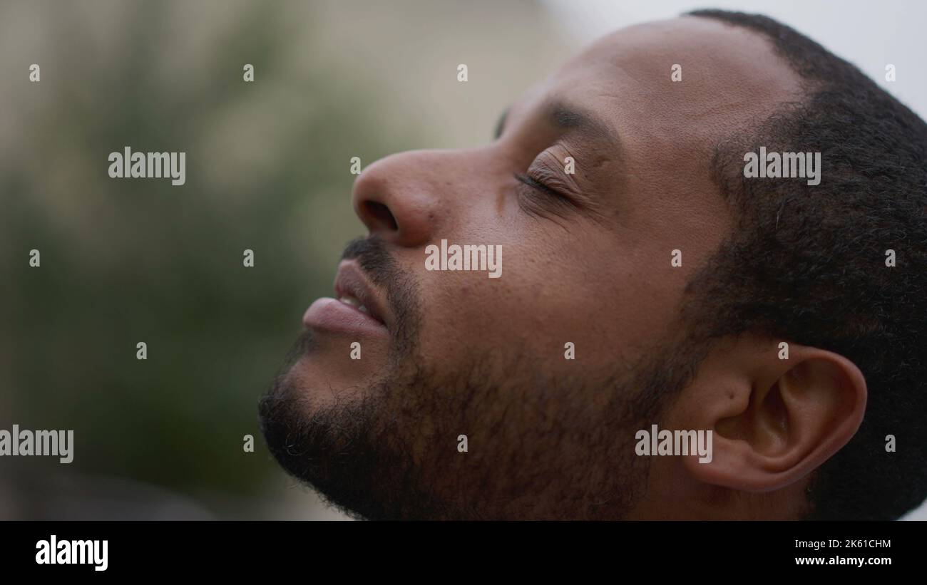 Hopeful African American man closeup face closing eyes in meditation ...
