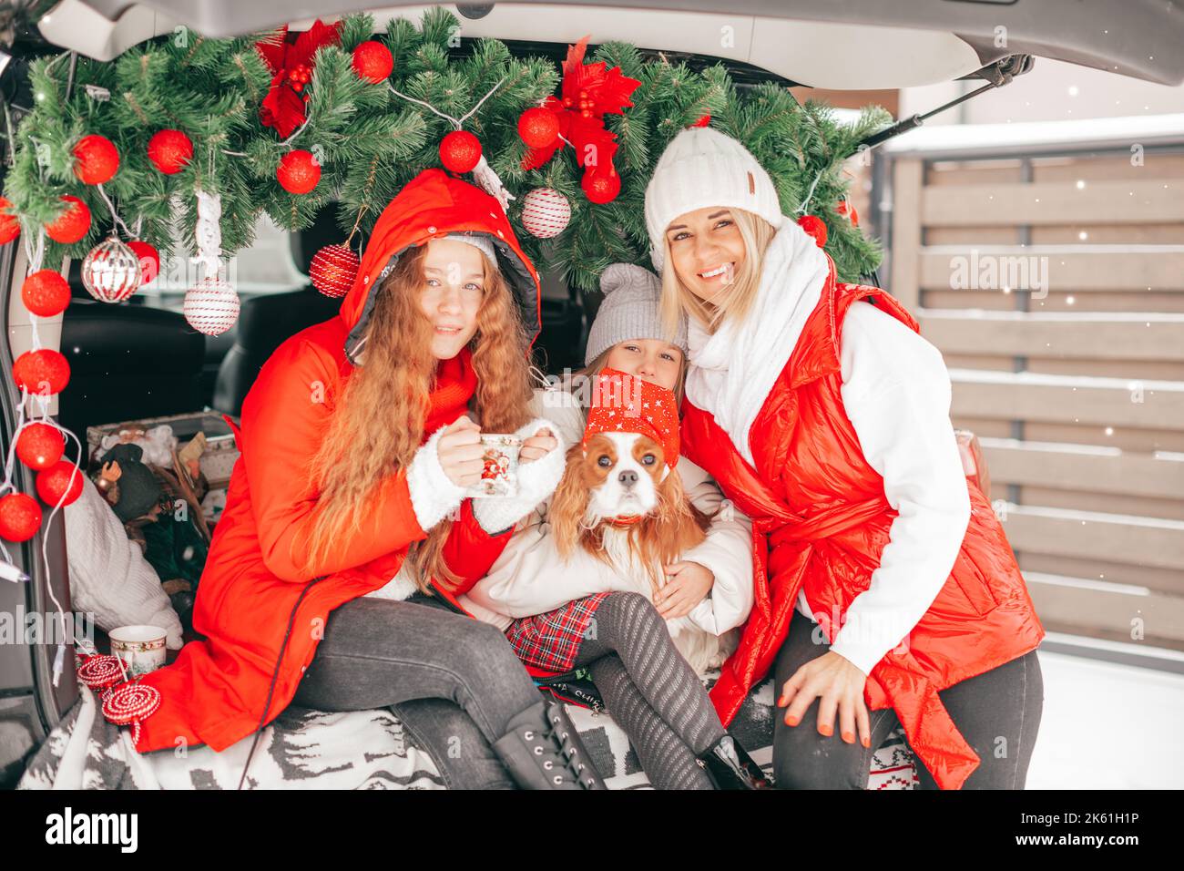 Merry Christmas and New Year party. Family in red winter clothes in car ...