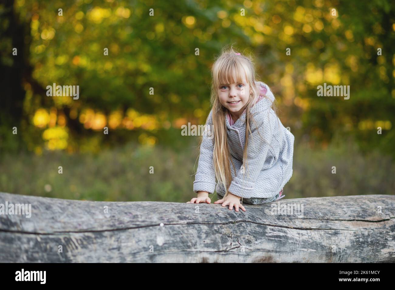 Cute baby girl on all fours balances on a fallen log Stock Photo - Alamy