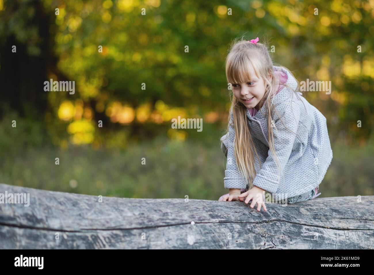 Cute baby girl on all fours balances on a fallen log Stock Photo - Alamy