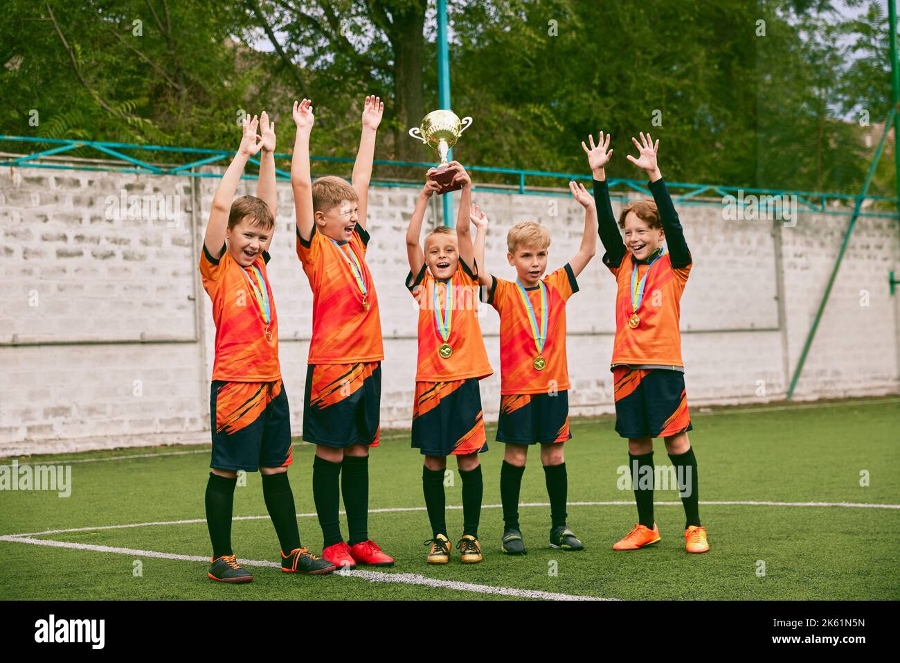 Soccer junior team with medals and trophy. Sportive boys celebrating victory. Concept of win ...