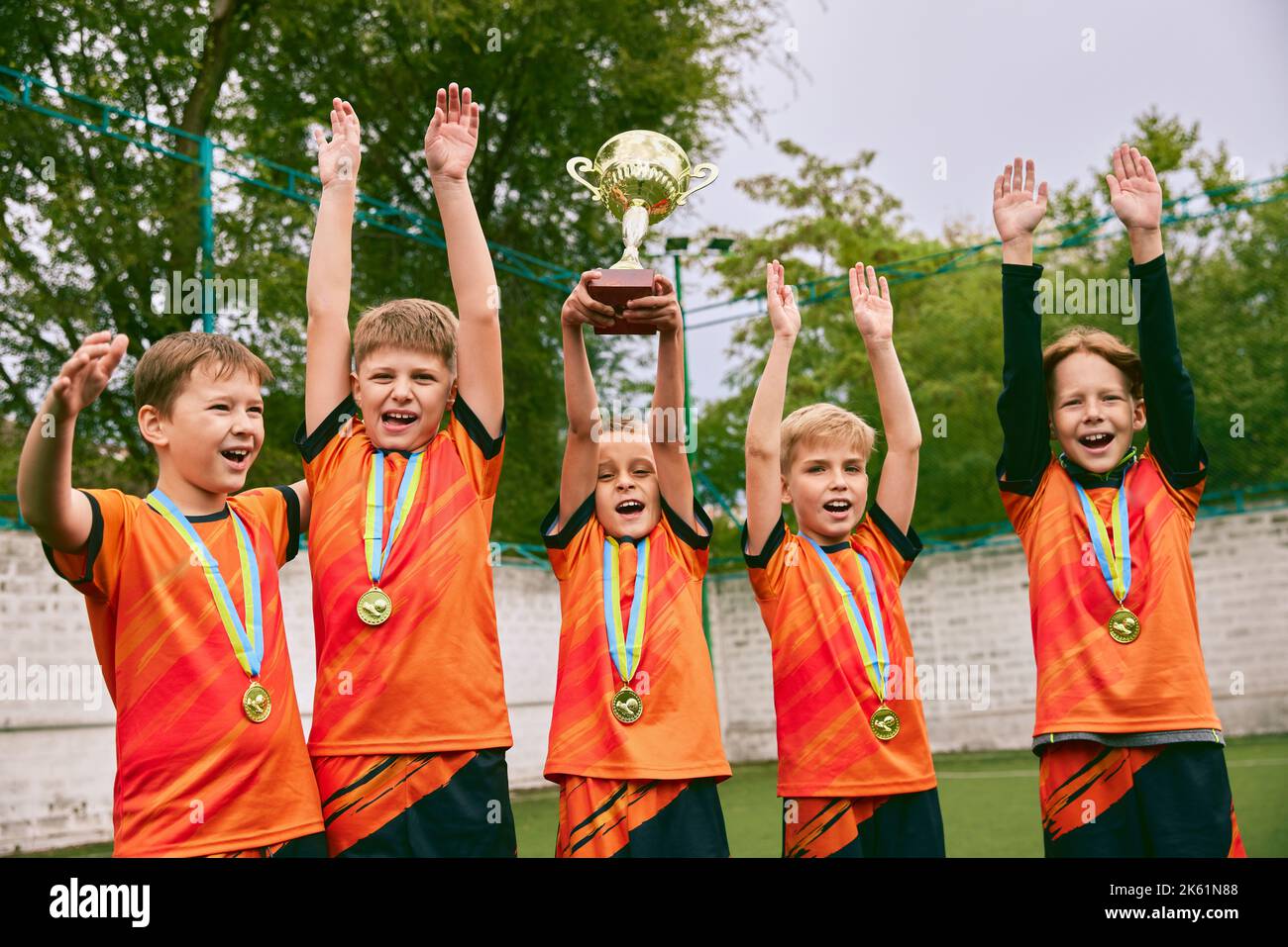 Soccer junior team with medals and trophy. Sportive boys celebrating victory. Concept of win ...