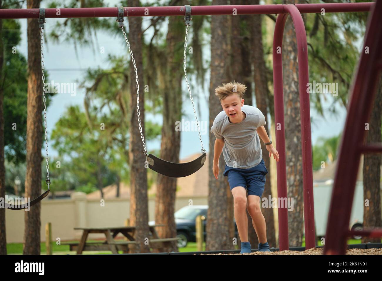 Young handsome smiling teenage boy jumping out of the swings on summer ...