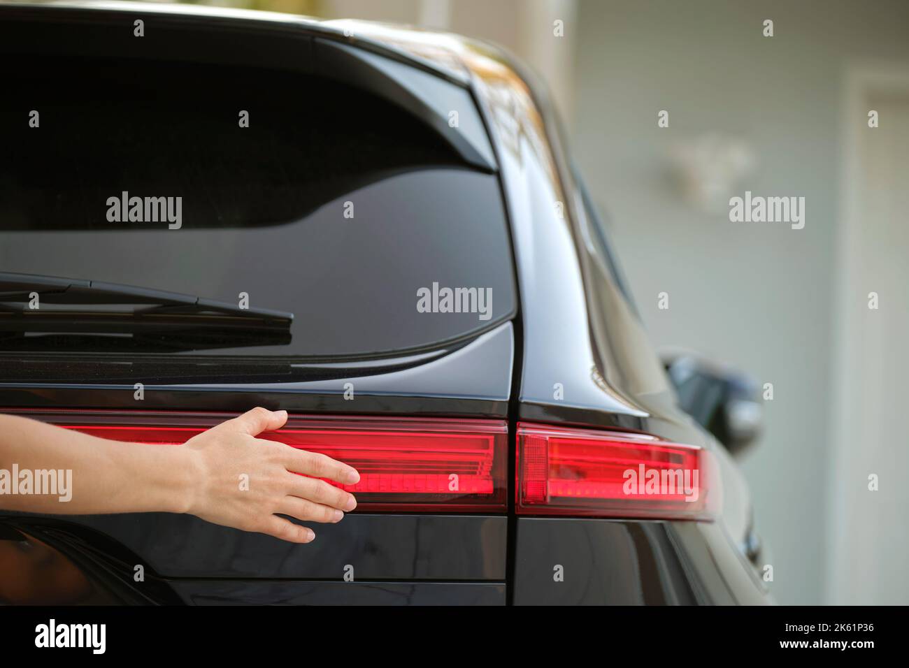 Close-up of human hand on rear car stoplight, checkout before driving ...