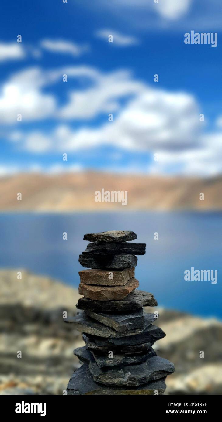 A vertical macro of rocks put together over a background of a lake ...
