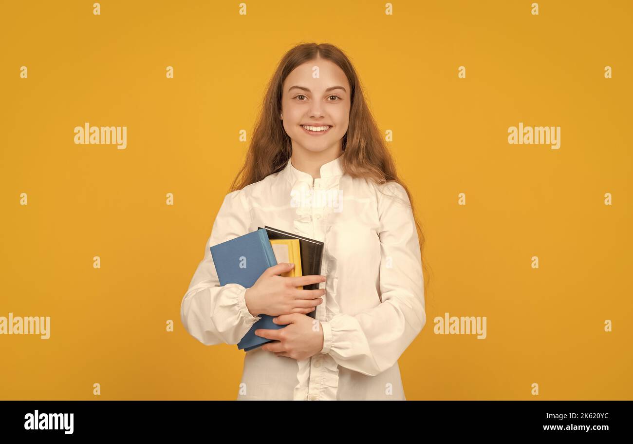 cheerful teen girl hold school workbook on yellow background ...