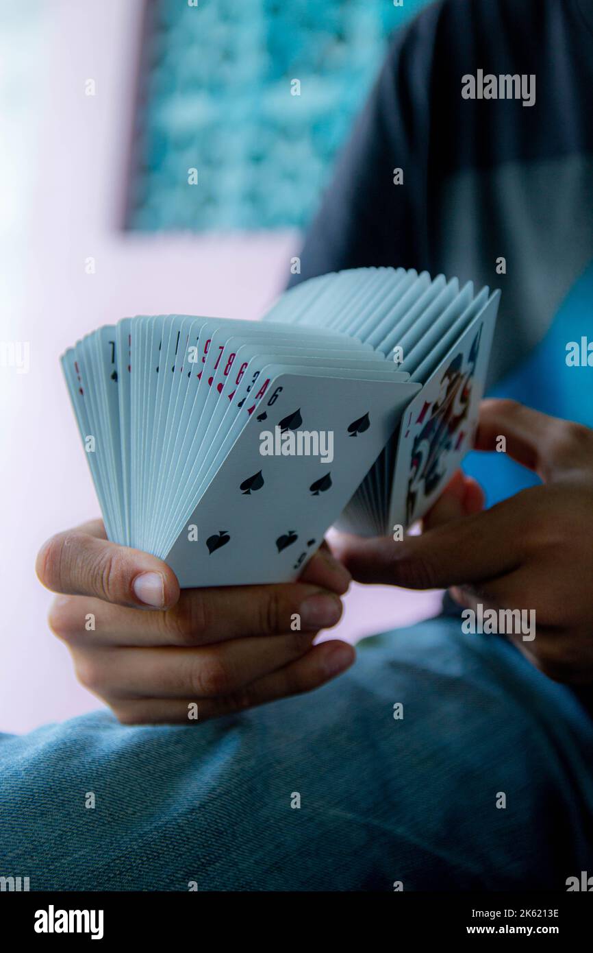 A vertical shot of a male doing a trick with a deck of poker cards ...