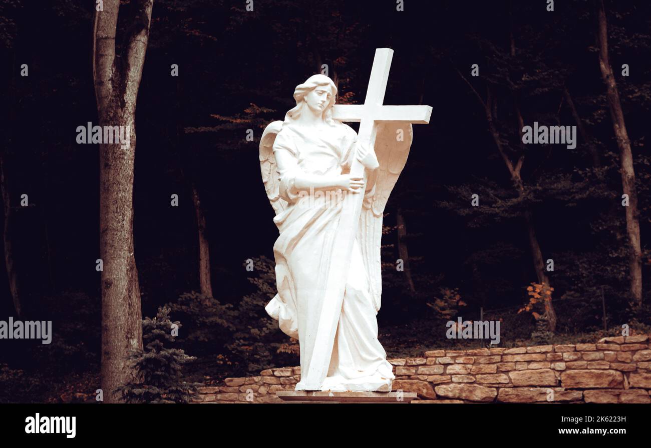 Ancient white stone holy angel with wings holding large cross Stock ...