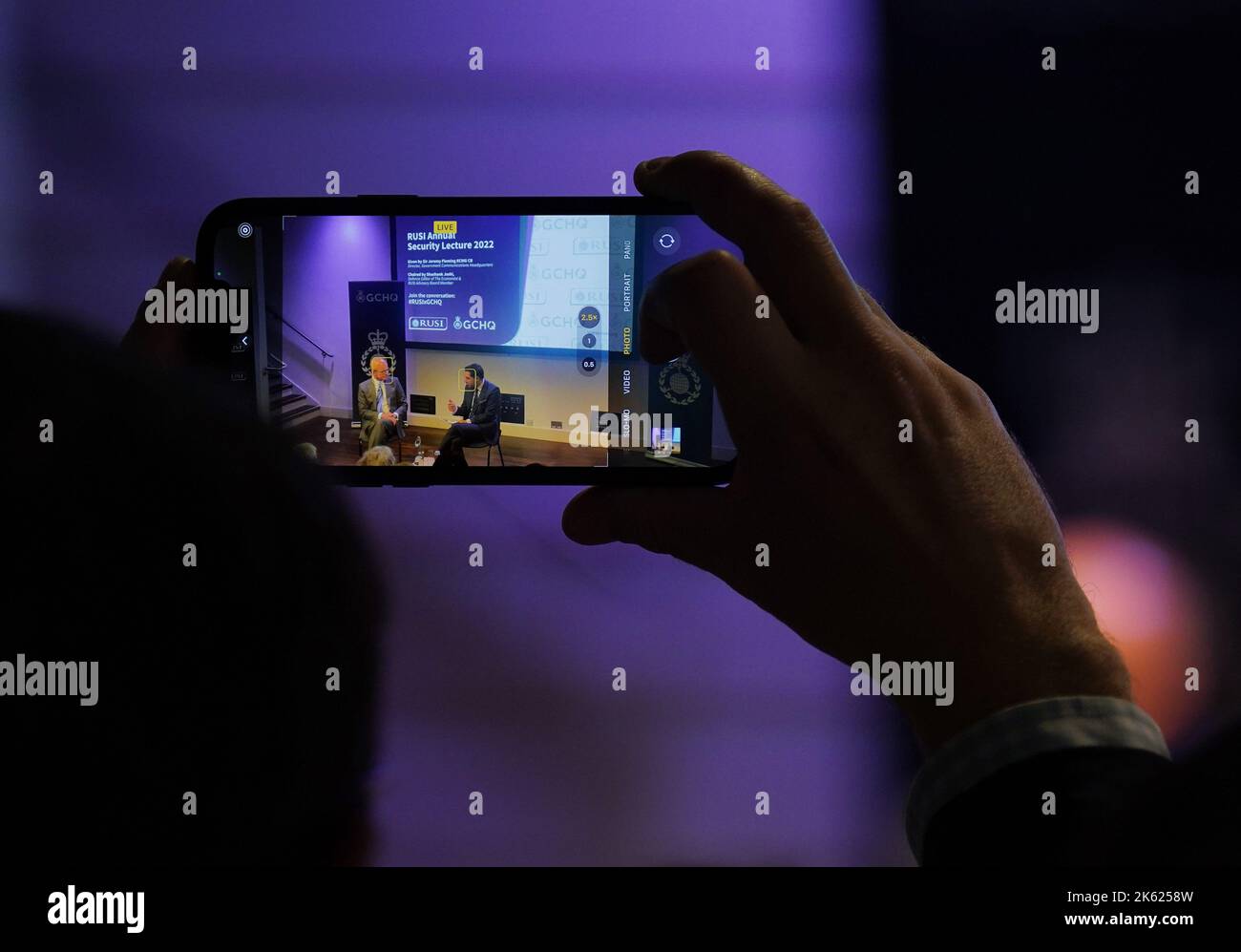A member of the audience uses a mobile phone to photograph Sir Jeremy ...