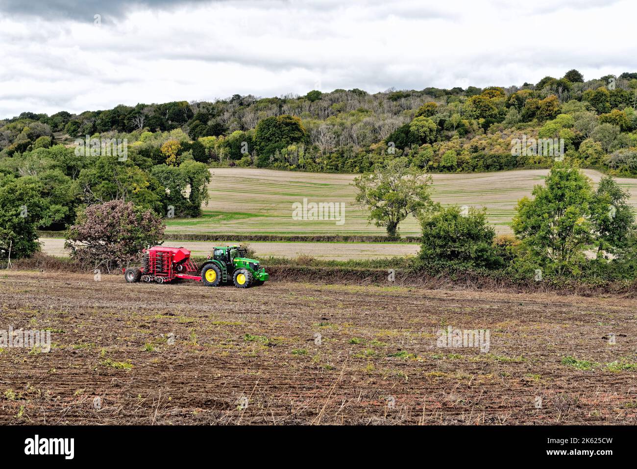 A green tractor with a red trailer working a field in the Surrey Hill's ...