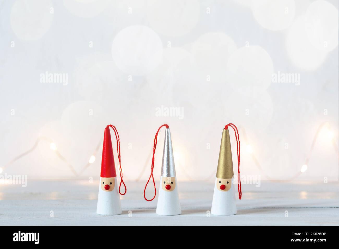 three Santa Clauses figurines on a white background, garland lights ...