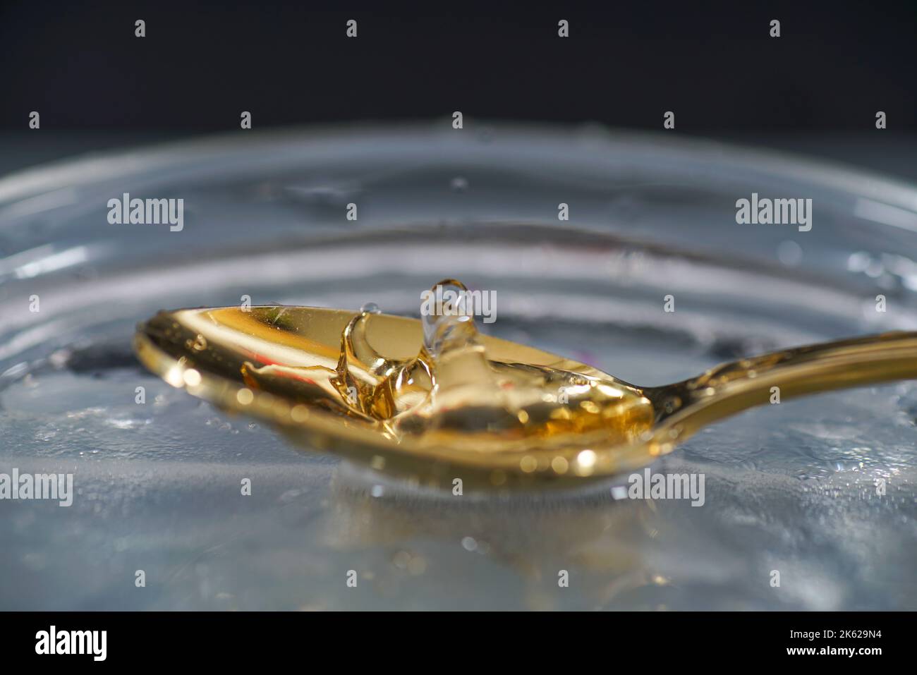 A closeup shot of a droplet of water floating on a golden spoon Stock ...