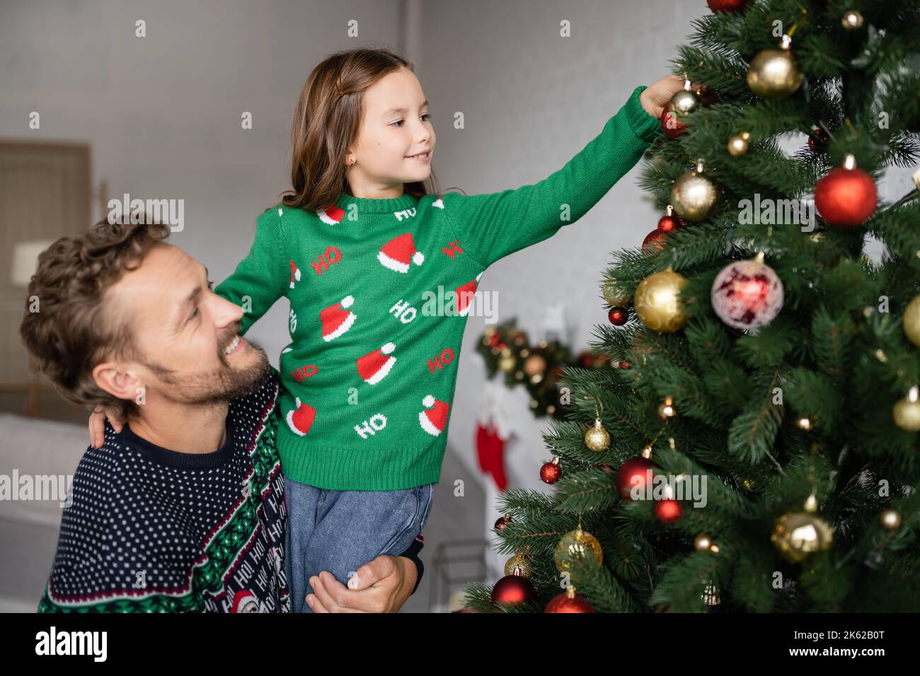 Positive father and daughter decorating christmas tree at home,stock ...