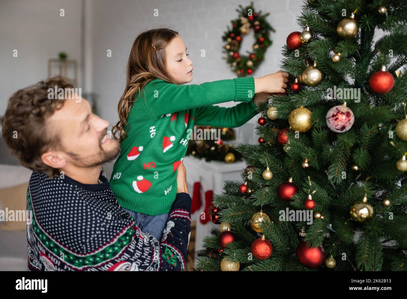 Smiling man holding daughter decorating christmas tree at home,stock ...