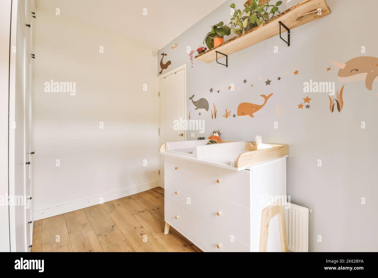 Comfortable chair placed near table with wardobe and shelves in light ...