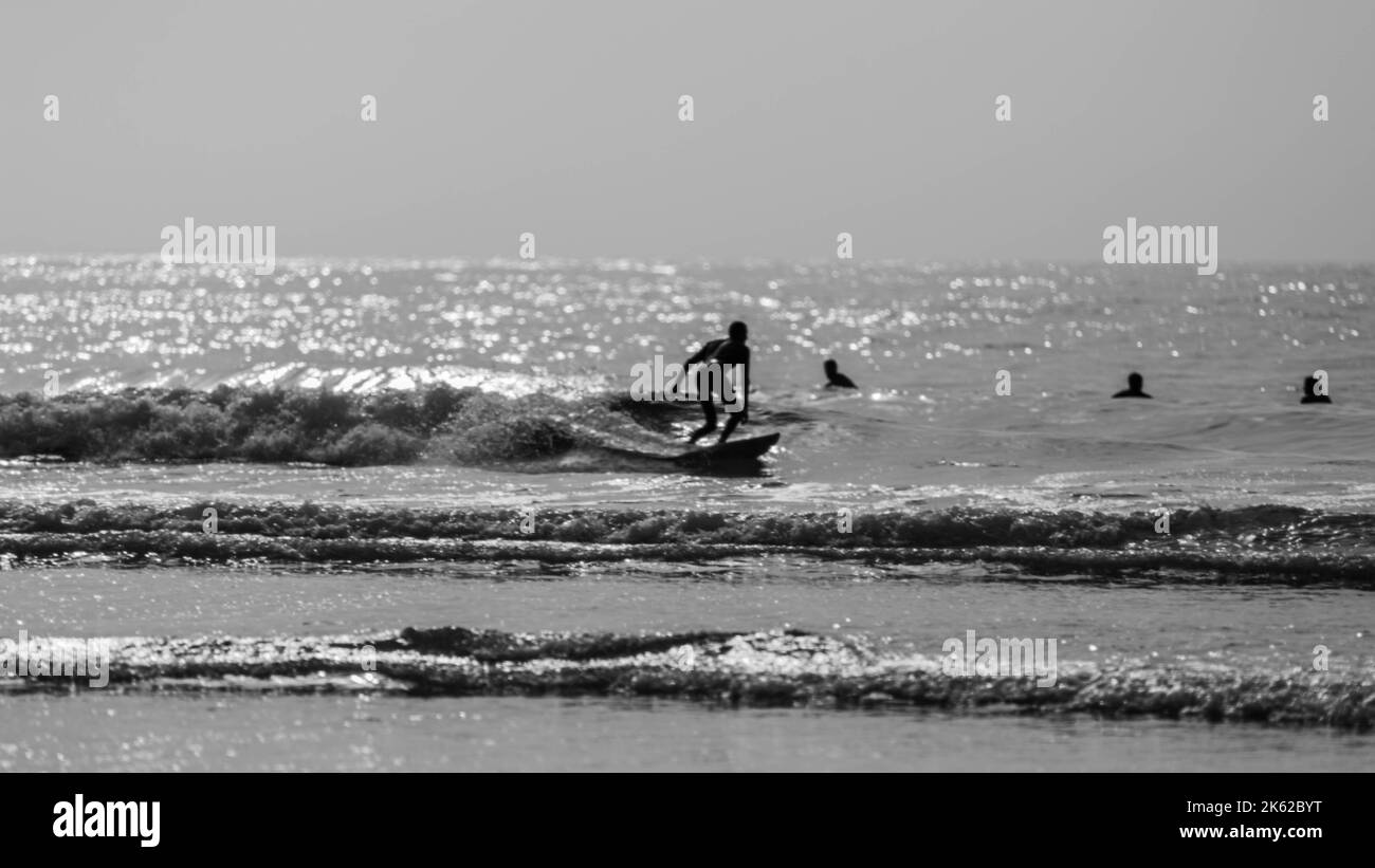 A man is surfing on a surfboard in Agadir beach in black and white ...