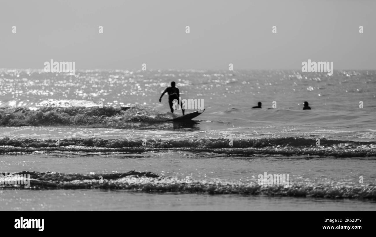 A man is surfing on a surfboard in Agadir beach in black and white ...
