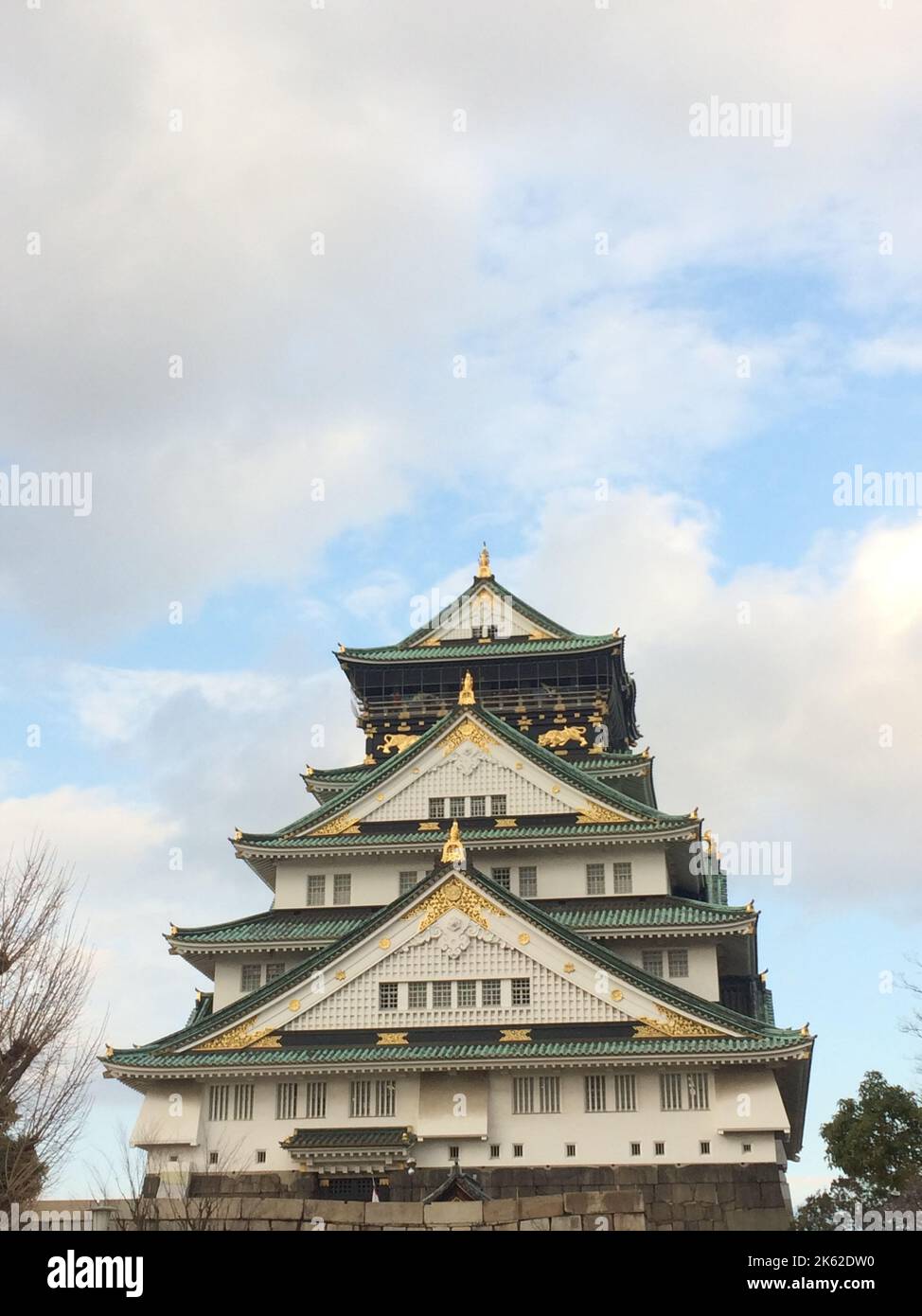 A vertical low-angle view of the Osaka Castle building under the cloudy ...