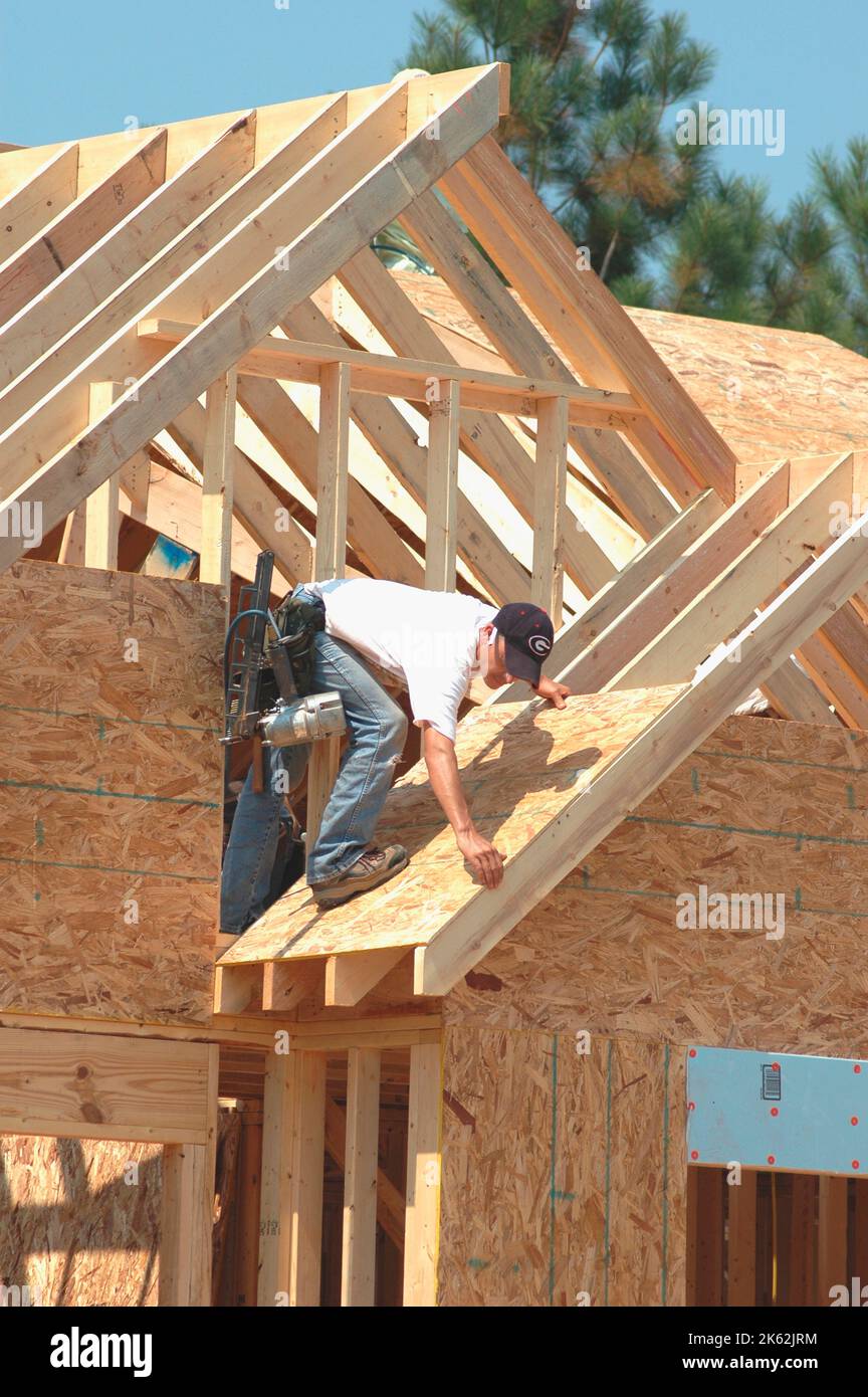 Roofers putting on sub roof of particle board on new home construction ...