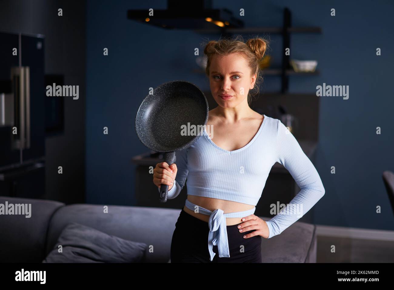 Young smiling caucasian female holding frying pan standing at home on a ...