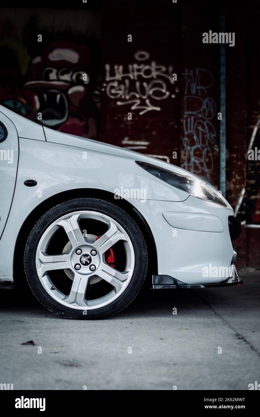 A vertical shot of a side view of a white car with a wheel parked ...