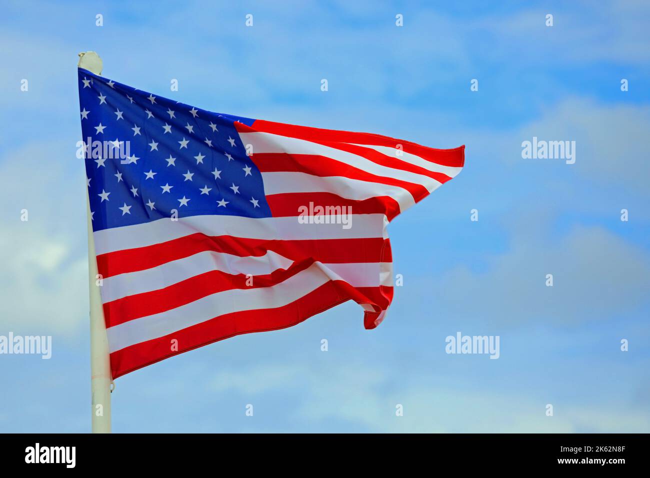 wide American Flag waving in the blue sky with some clouds Stock Photo ...
