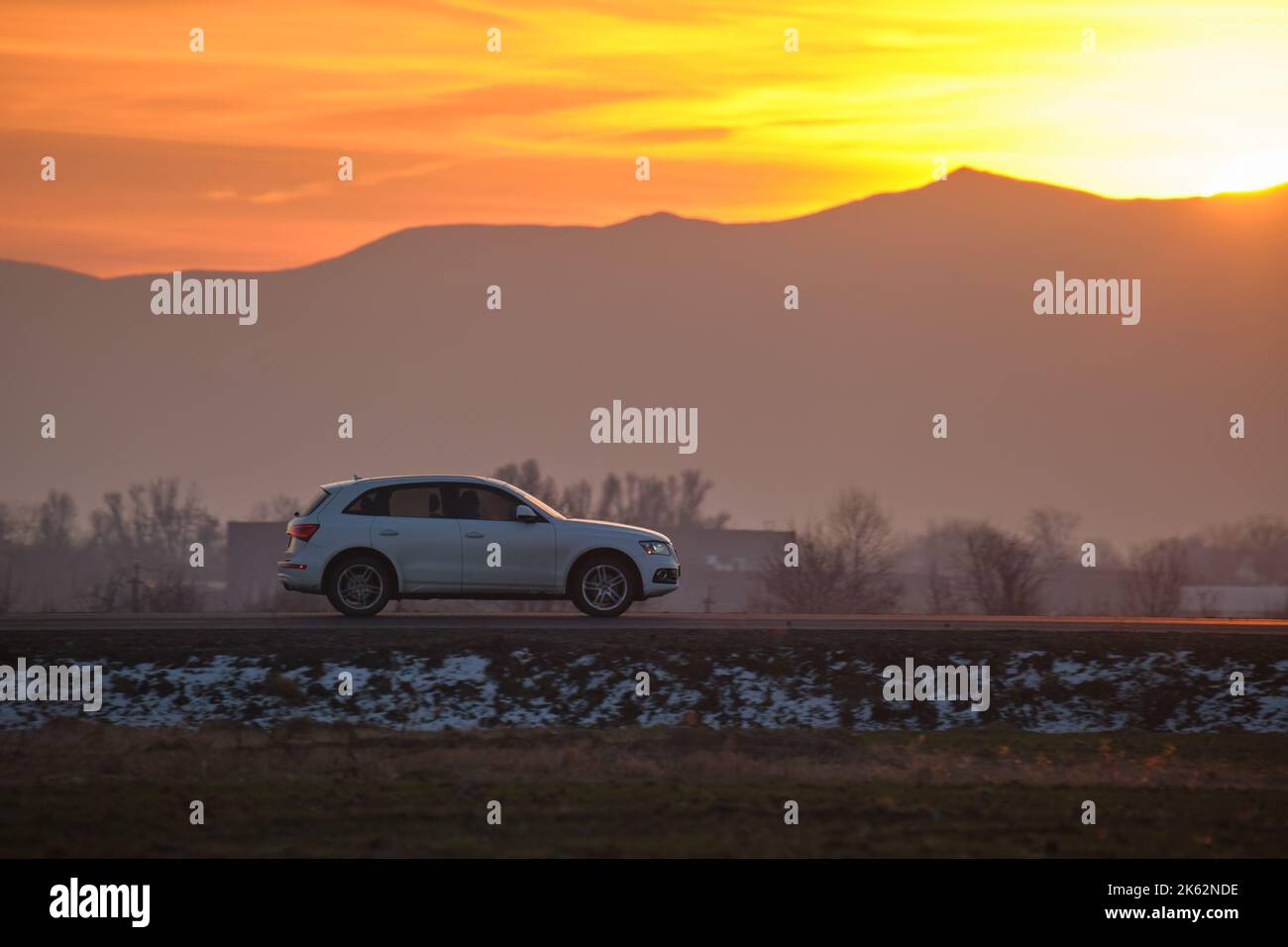 SUV car driving fast on intercity road at sunset. Highway traffic in ...