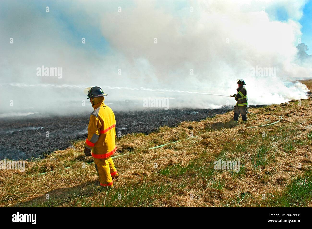 Firemen fighting a small brush fire in the Atlanta area with water and ...