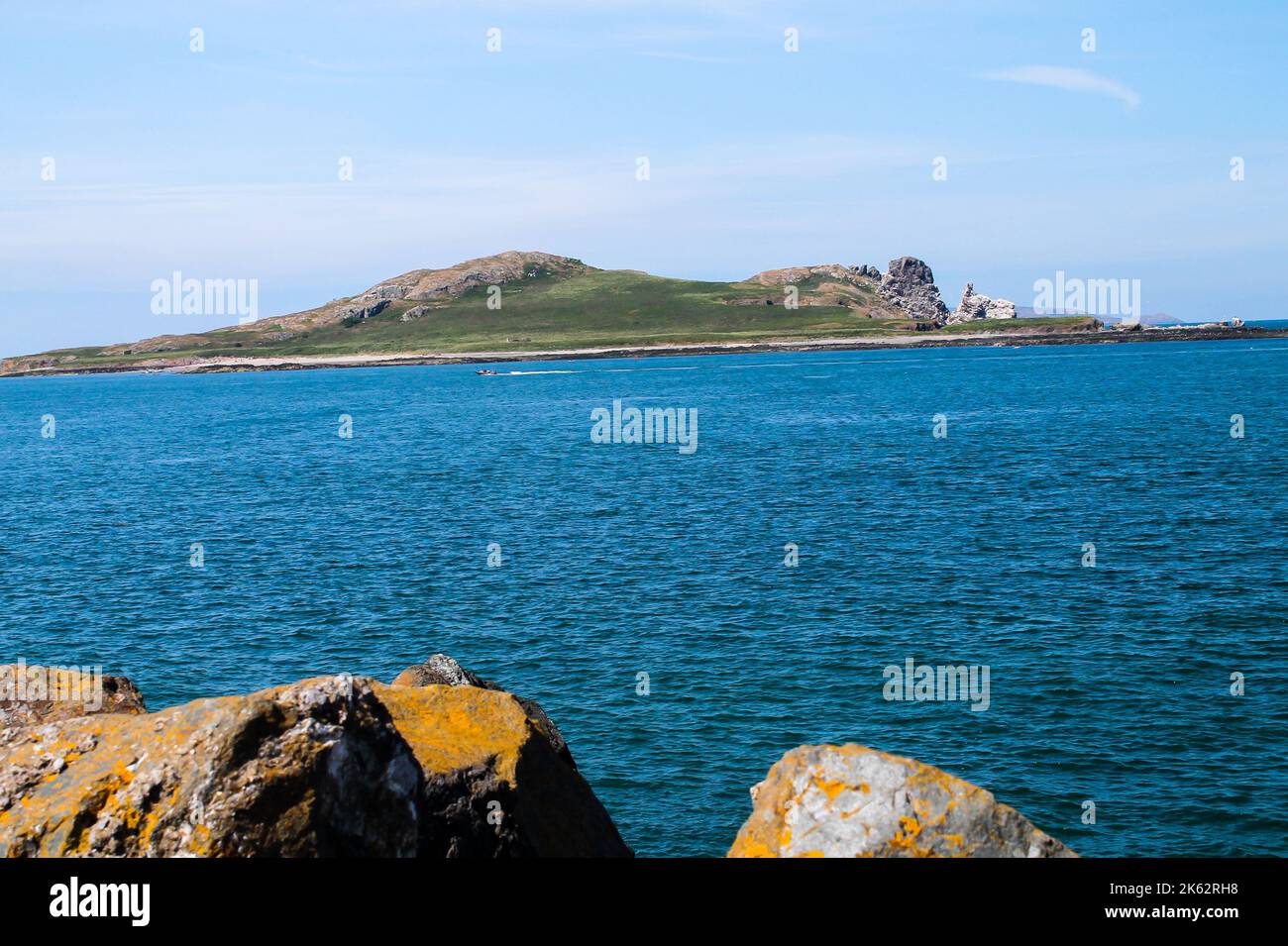 A closeup of Howth Dublin rocky beach with the blue clear sea and sky ...