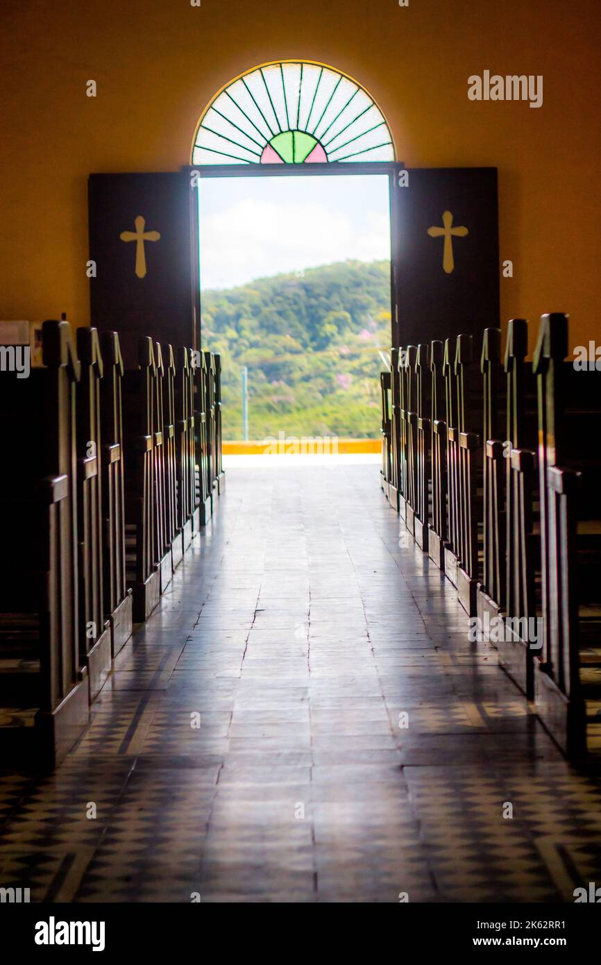 A vertical closeup of a church entrance from inside with pews around ...