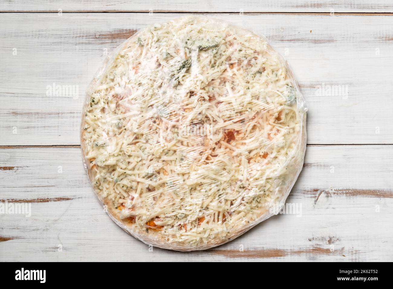 Frozen pizza in plastic wrap. Semifinished Stock Photo - Alamy