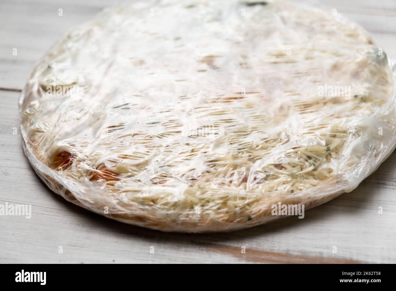 Frozen pizza in plastic wrap. Semifinished Stock Photo - Alamy