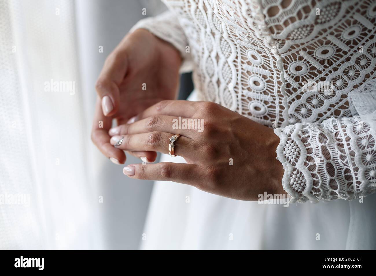 Gentle female hands of the bride with a gold wedding ring on the ring ...