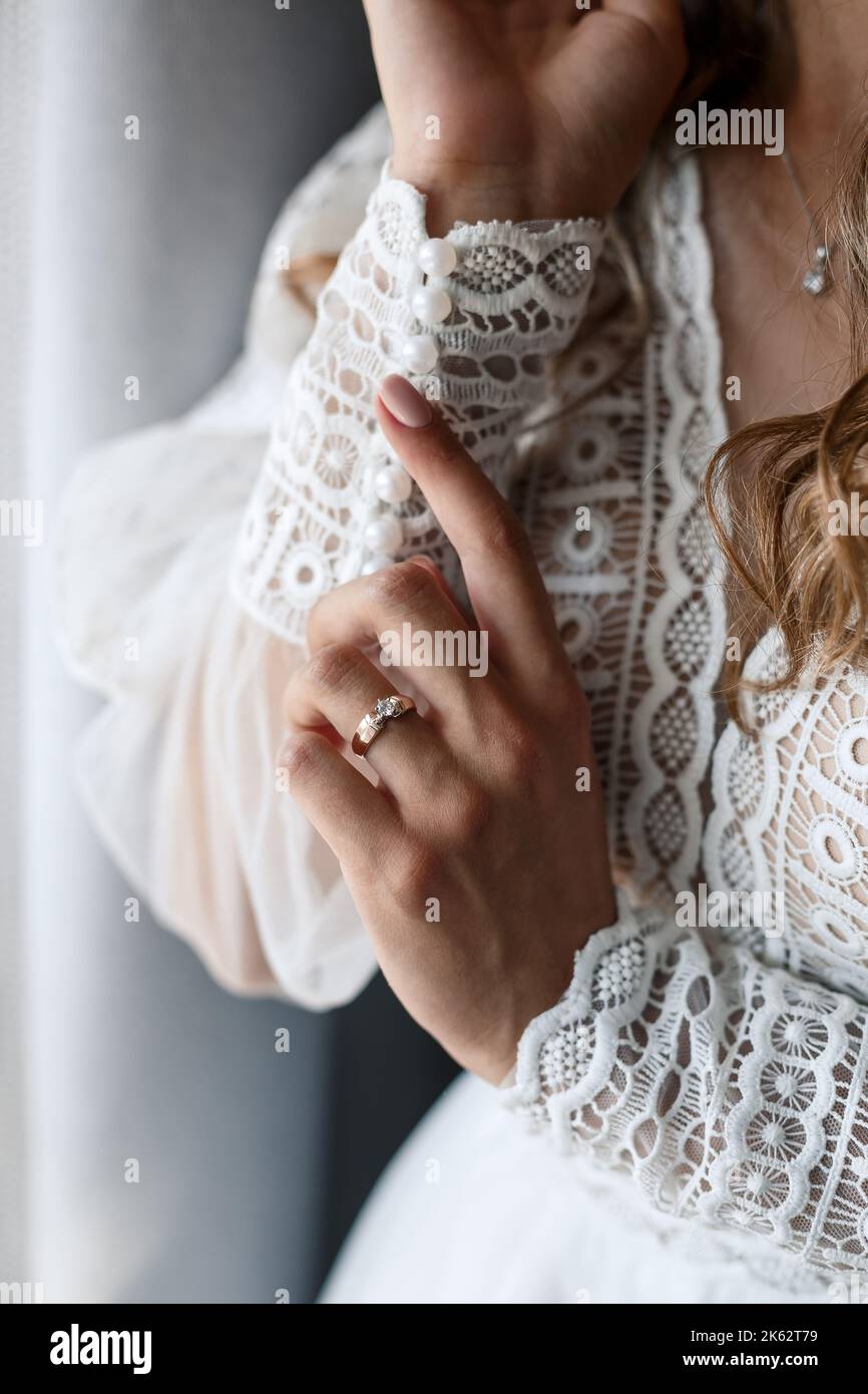 Gentle female hands of the bride with a gold wedding ring on the ring ...