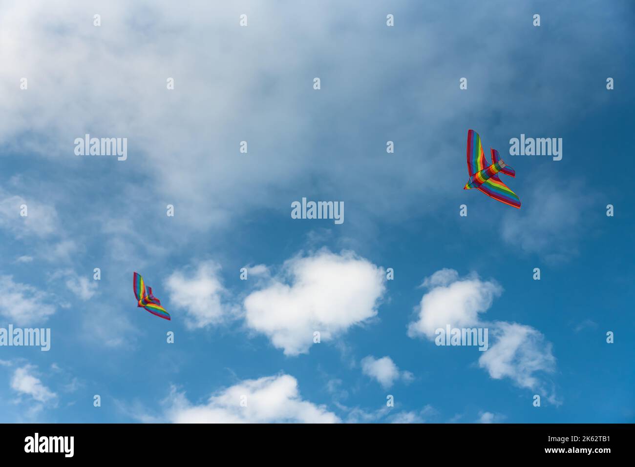 Two colorful kites in a blue sky with white clouds - focus on the kite ...