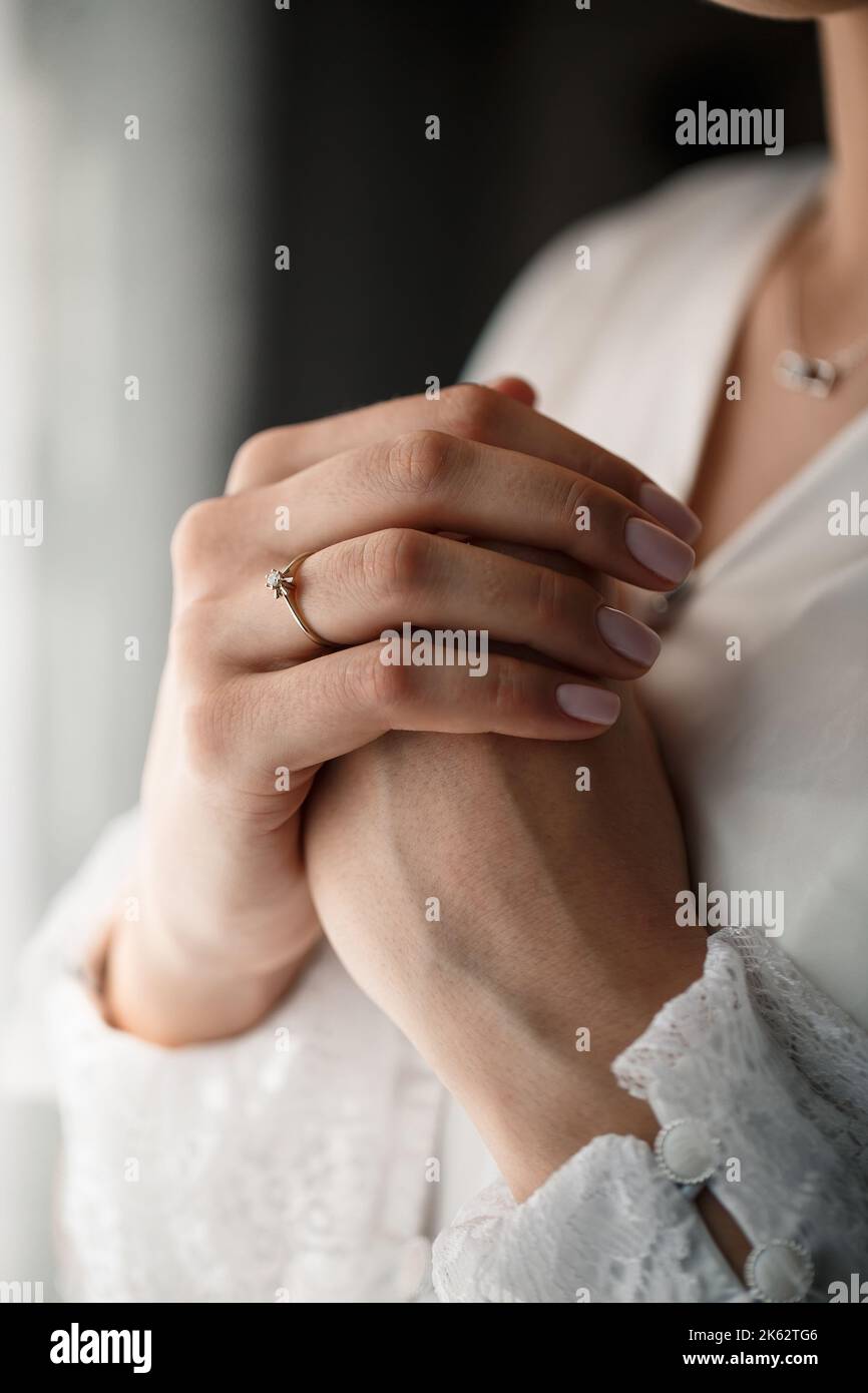 Gentle female hands of the bride with a gold wedding ring on the ring ...