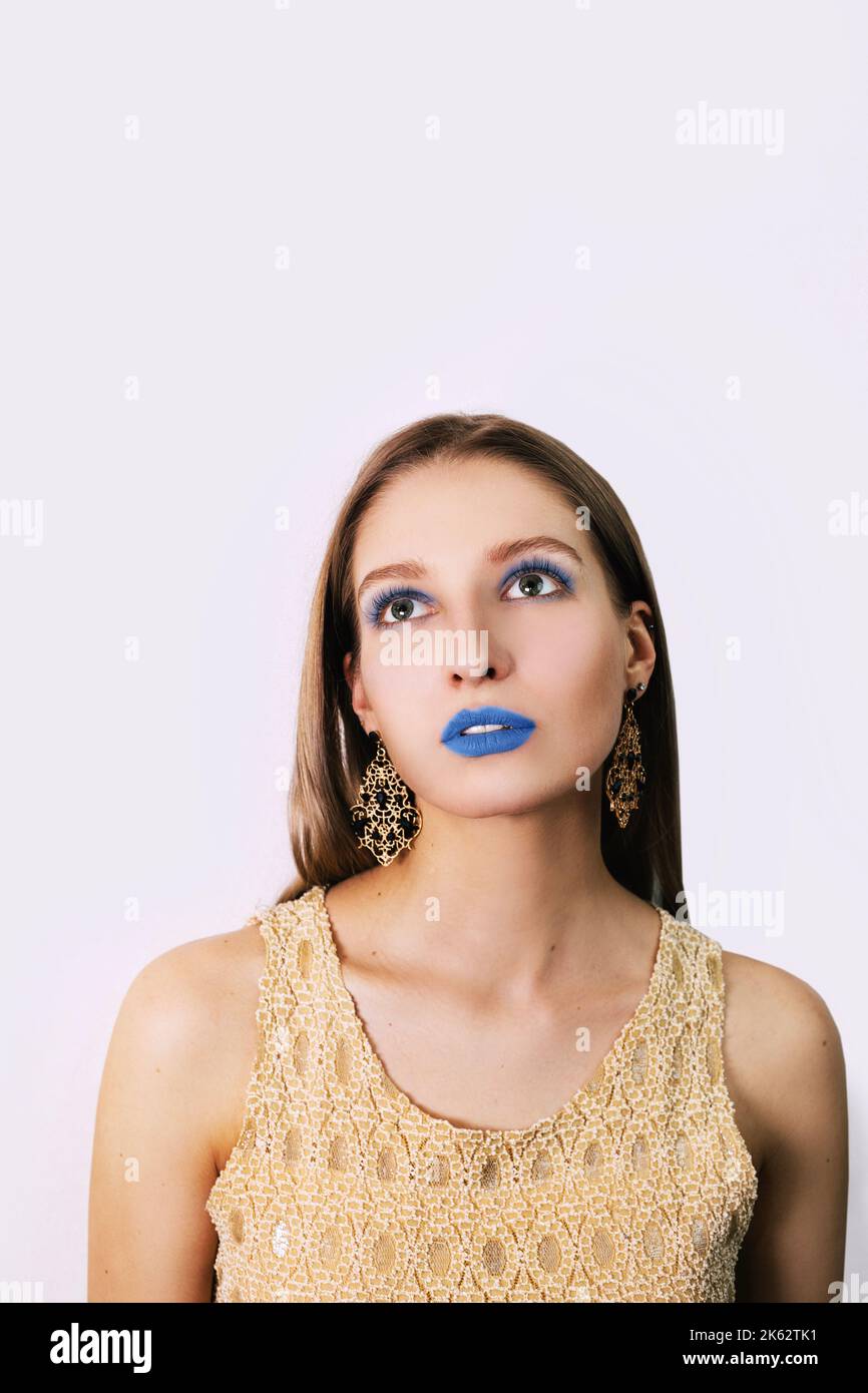 Portrait of pretty blonde girl with extreme, blue-yellow make-up; she ...