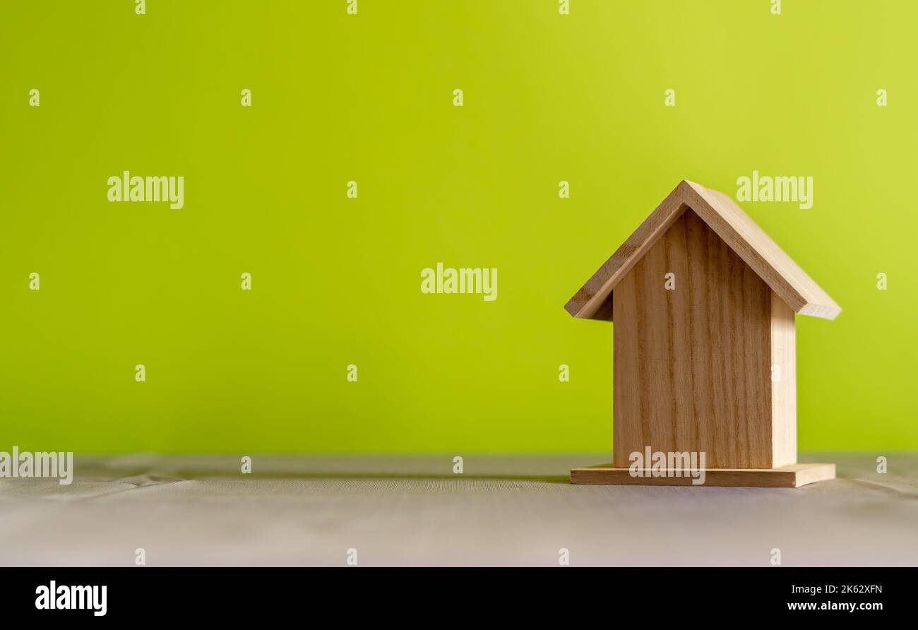 Property concept. Small wooden house on green background with space on ...