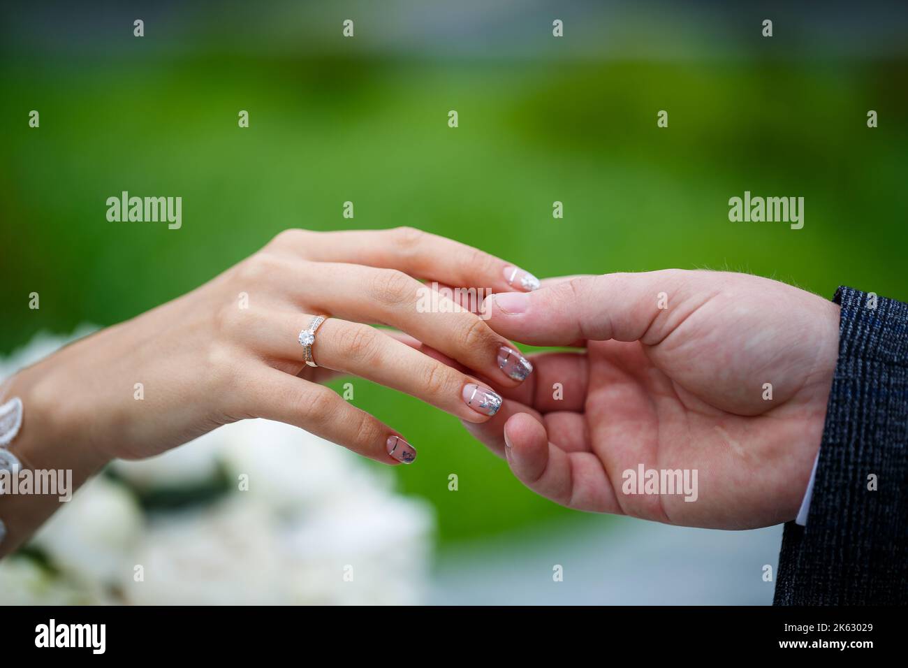 Gentle female hands of the bride with a gold wedding ring on the ring ...